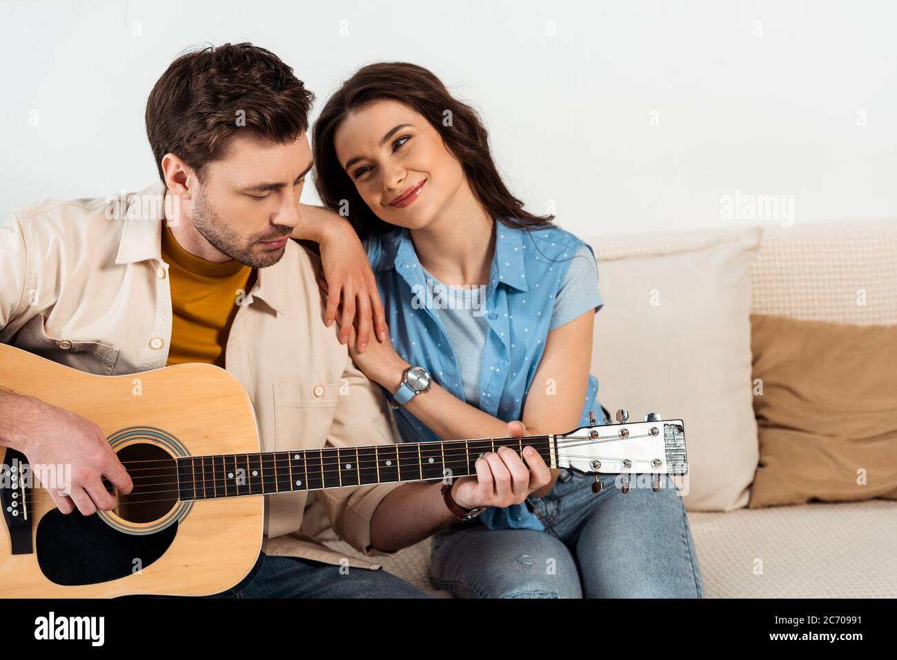 Smiling woman hugging and looking at boyfriend performing on acoustic ...
