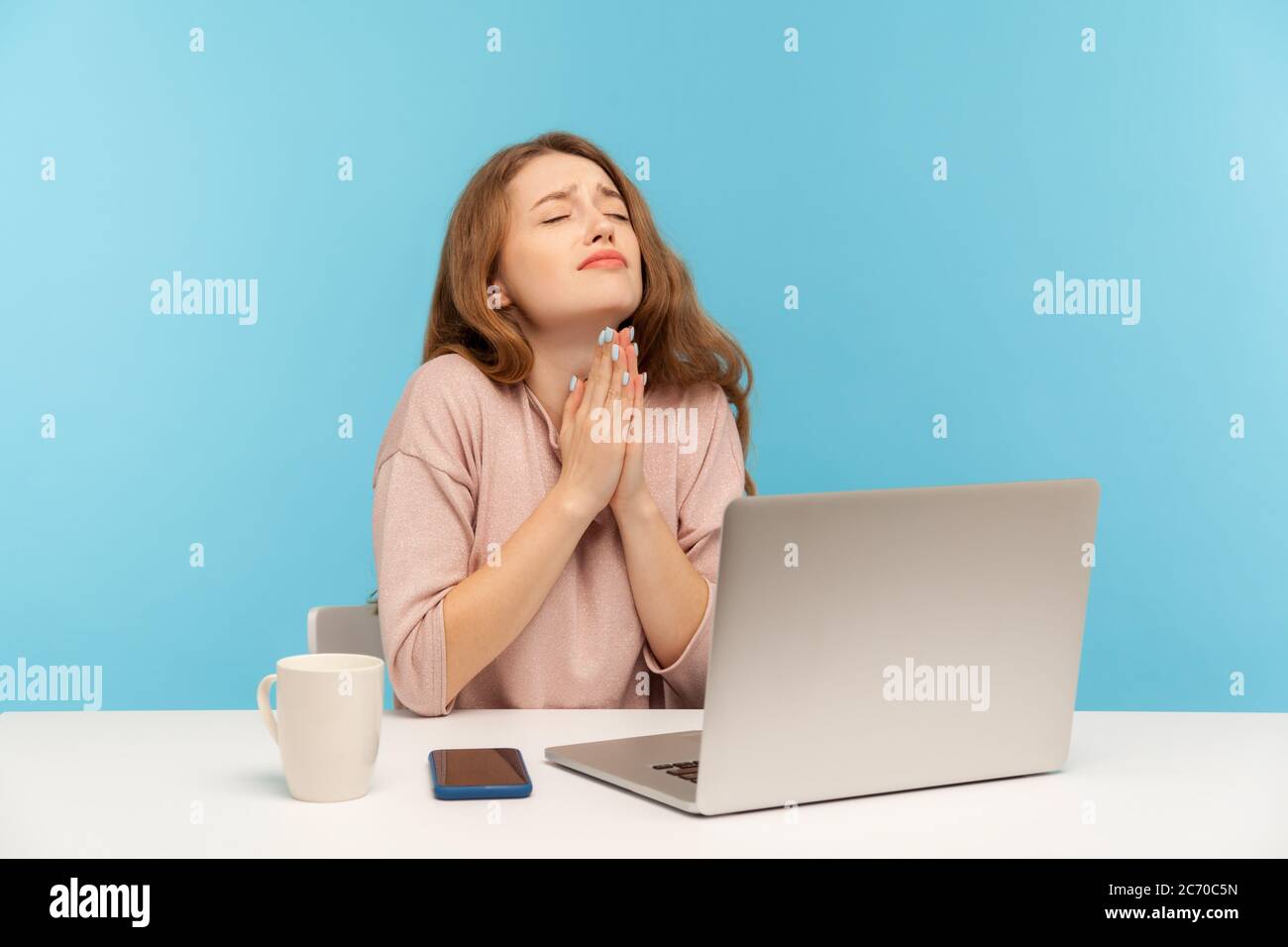 Please, god help! Young woman employee sitting at workplace and keeping ...