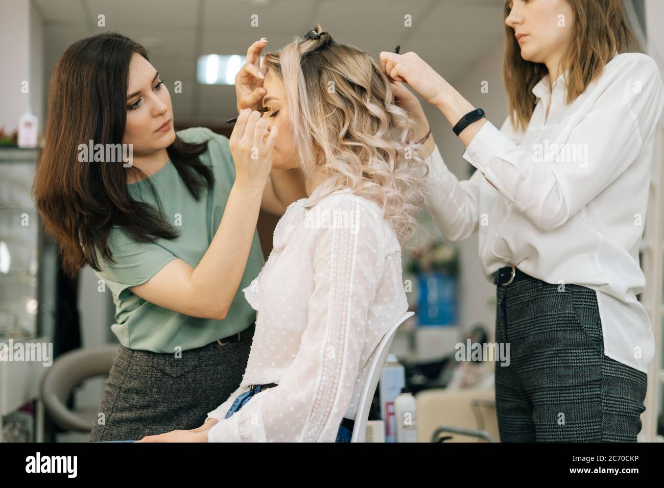 Professional female hairdresser make-up artist making hairstyle ...