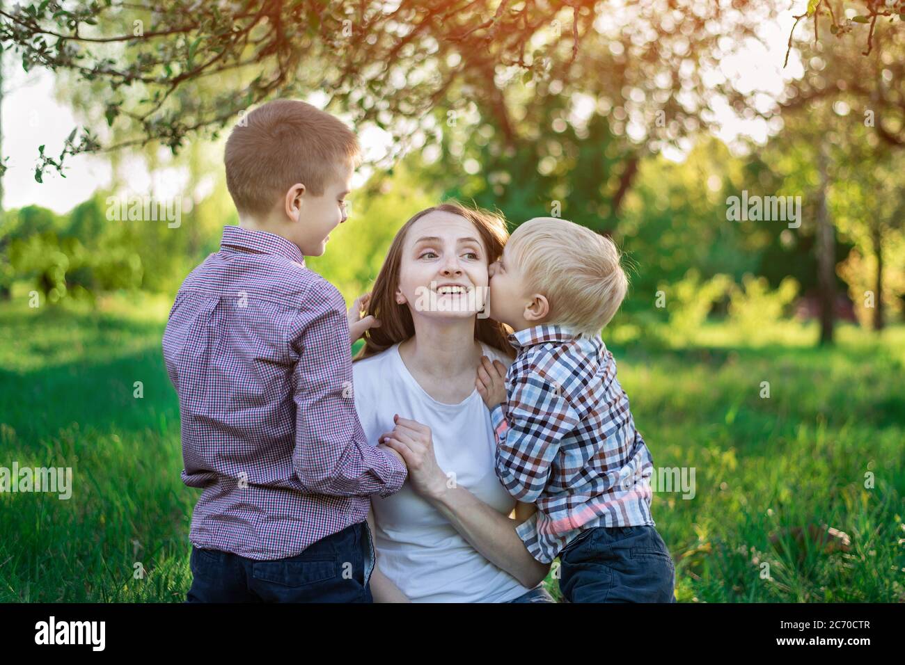 Mom with two sons in the Park. Child is kissing his mother. Happy ...