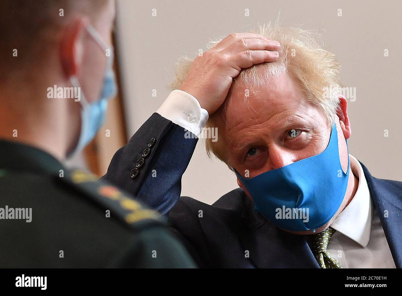 Prime Minister Boris Johnson, wearing a face mask, talks with a ...
