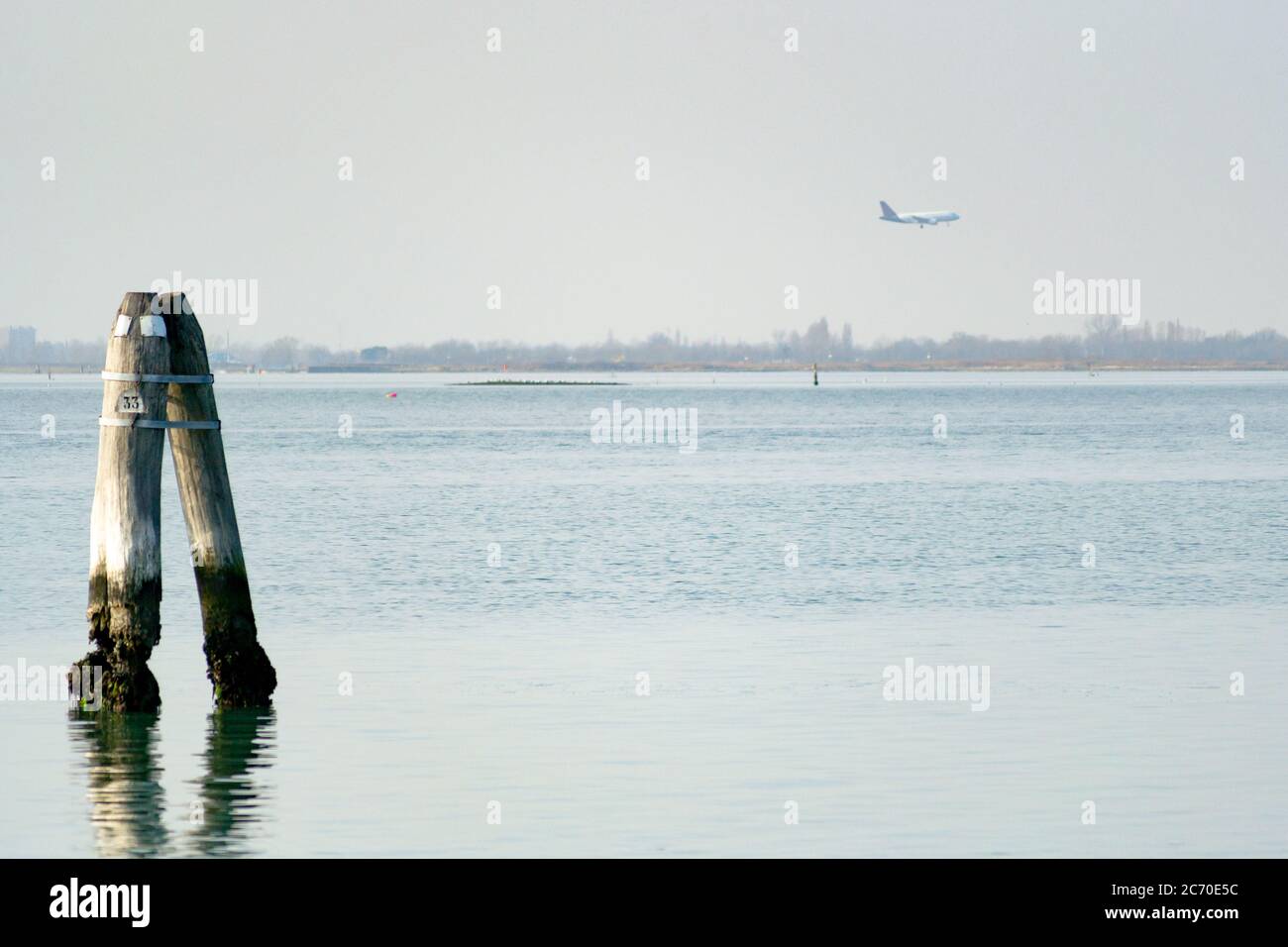 Venetian lagoon landscape. Navigation poles in the water in fore ground ...