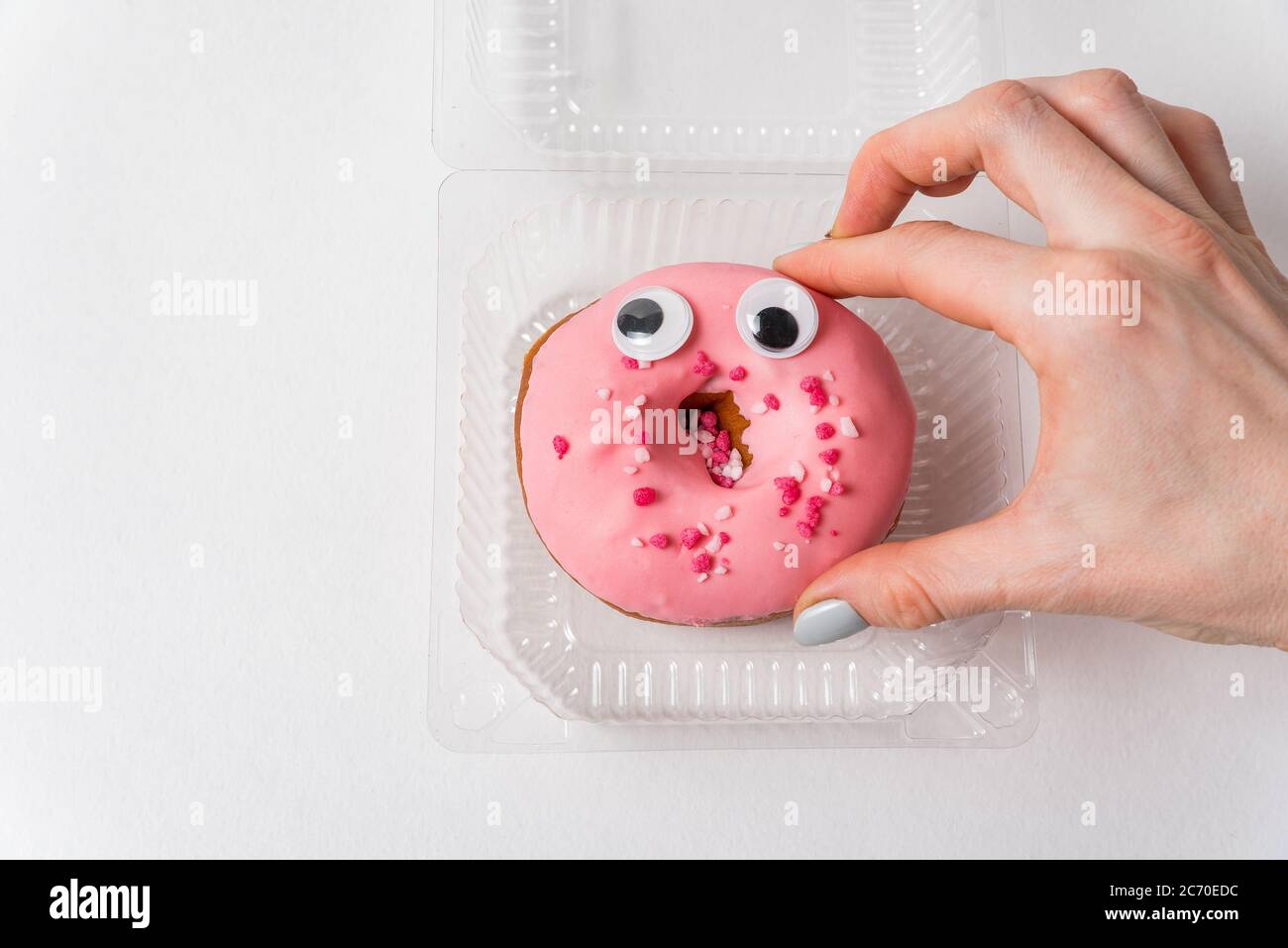 Funny shock face pink donut on white background. Female hand taking ...