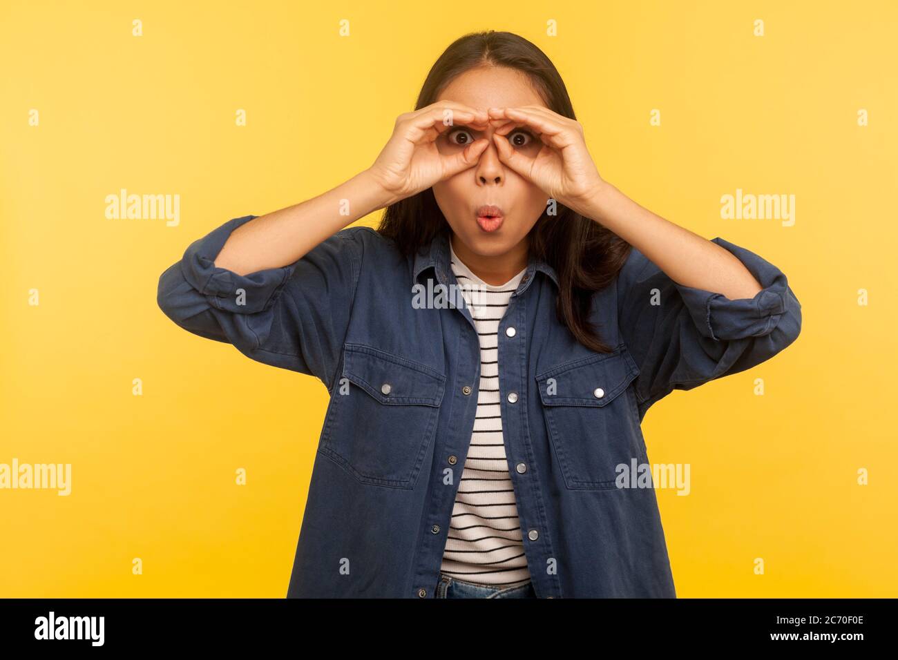 Portrait of amazed curious girl in denim shirt looking through ...