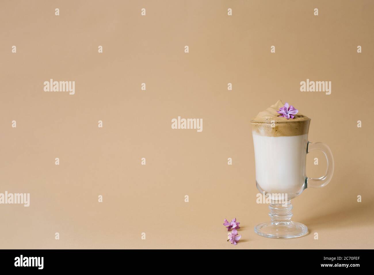 Beautiful dalgon coffee drink with foam in a transparent Cup and lilac ...