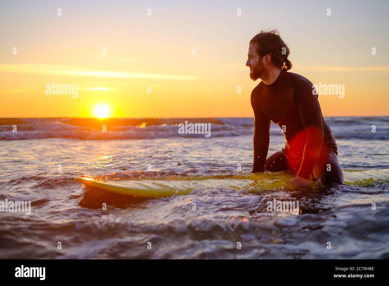 Surfer sitting on surfboard in sea Stock Photo - Alamy