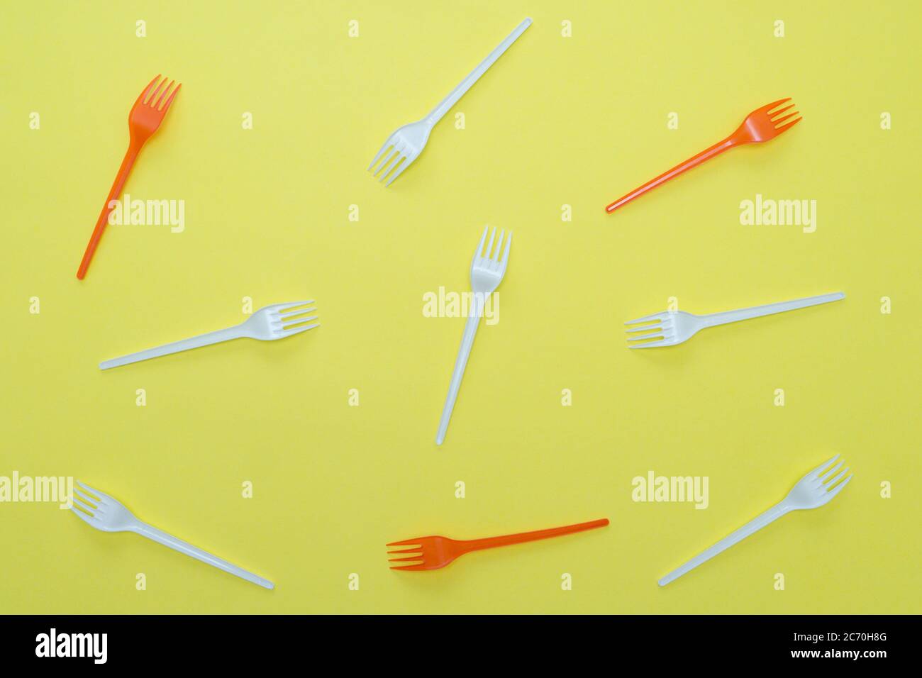Plastic white and red forks on yellow background. Environmental concept ...