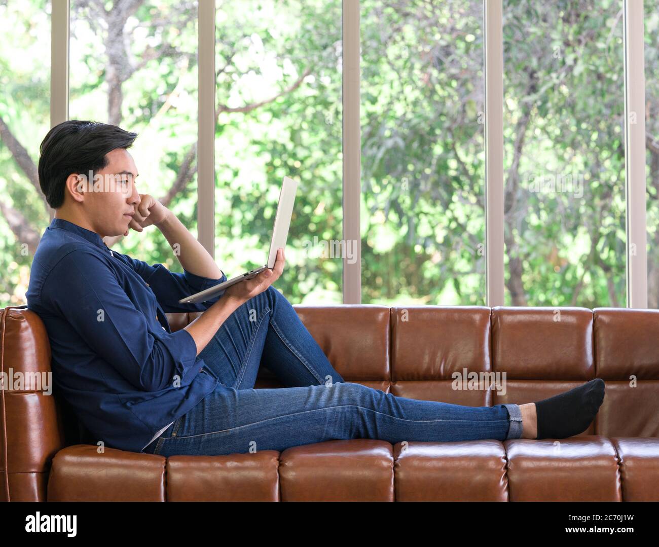 Young man use laptop computer to search for jobs. Asian man spend ...