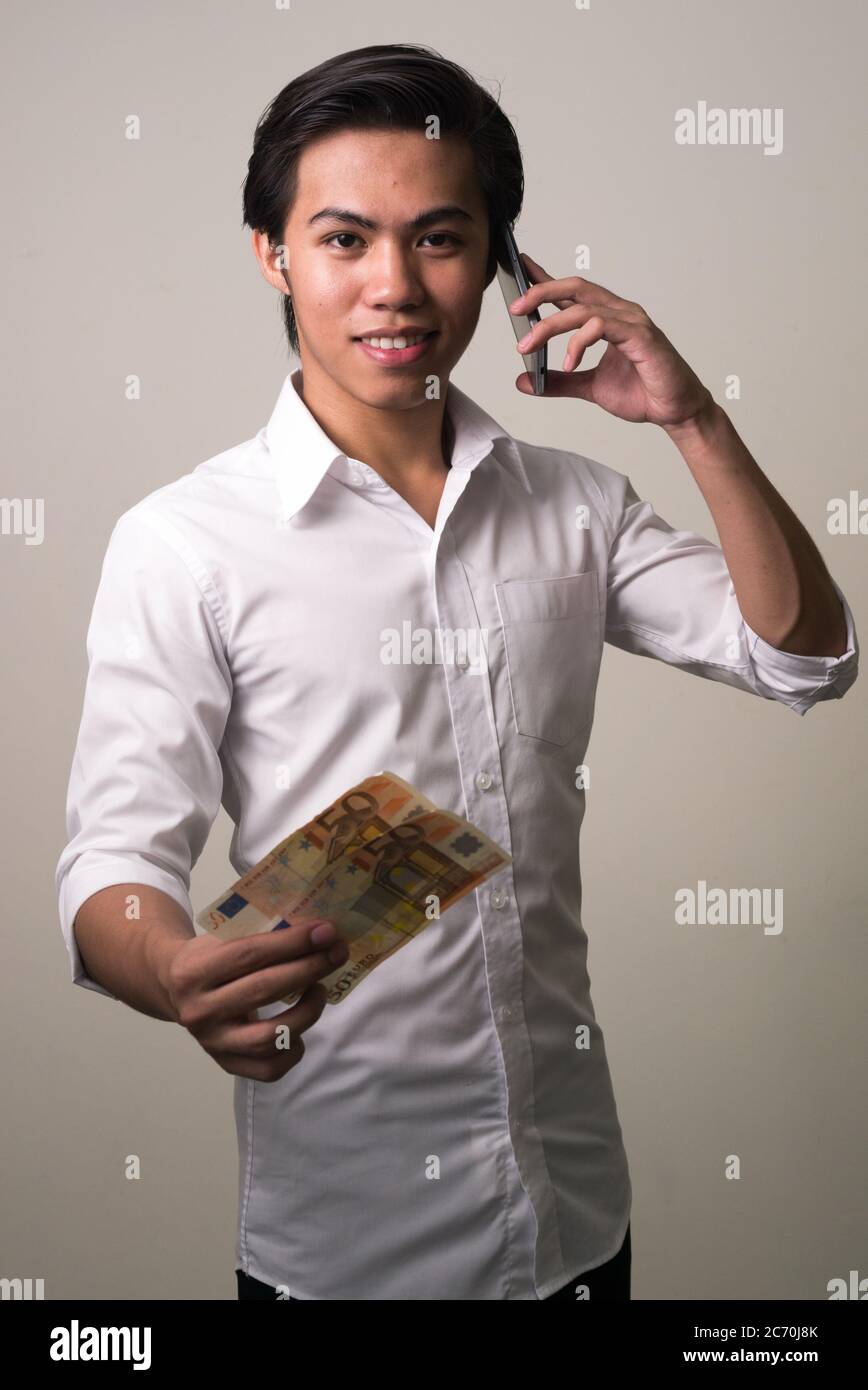 Portrait of happy young Filipino businessman talking on the phone and ...