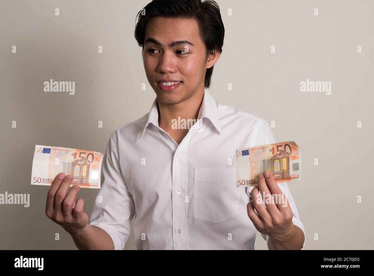 Portrait of happy young Filipino businessman holding money Stock Photo ...