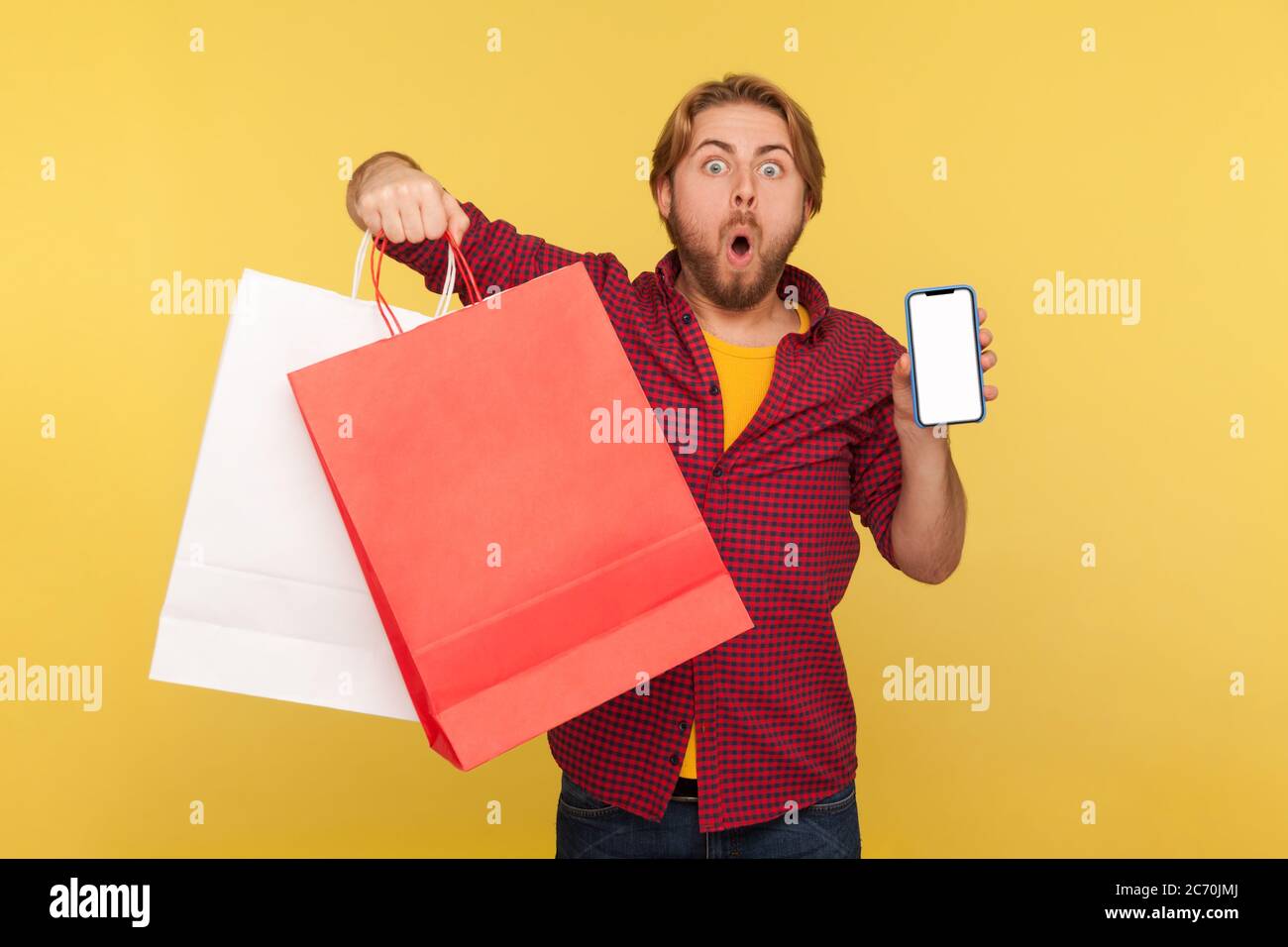 Amazed handsome shopper guy in checkered shirt holding shopping bags ...