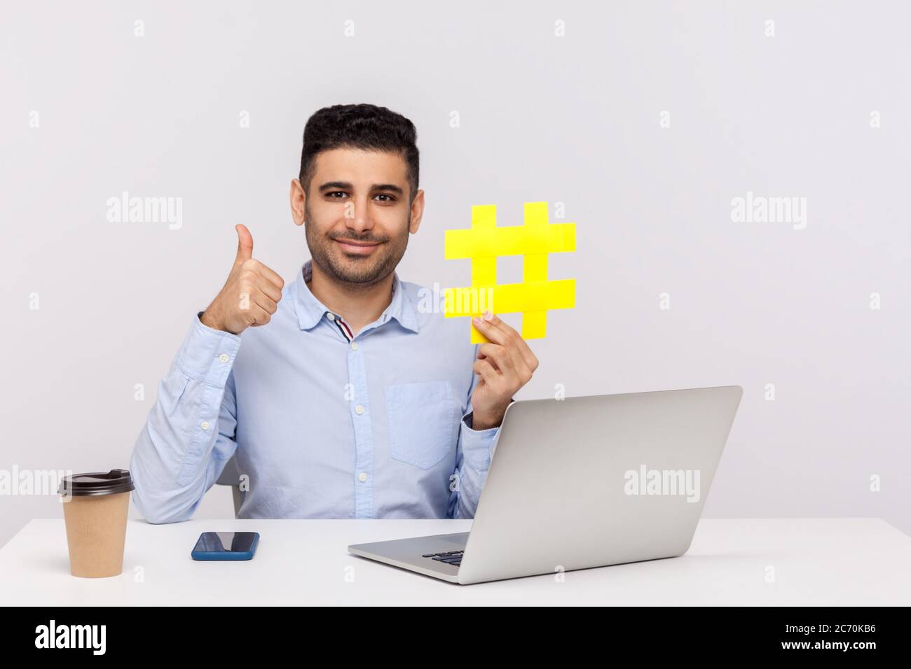 Businessman sitting in office workplace with laptop, holding big ...