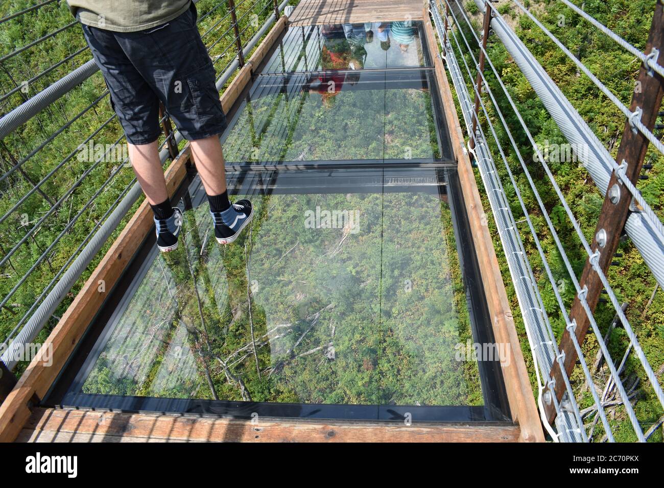 Boy standing on glass panels in floor of pedestrian Skybridge in Smoky ...