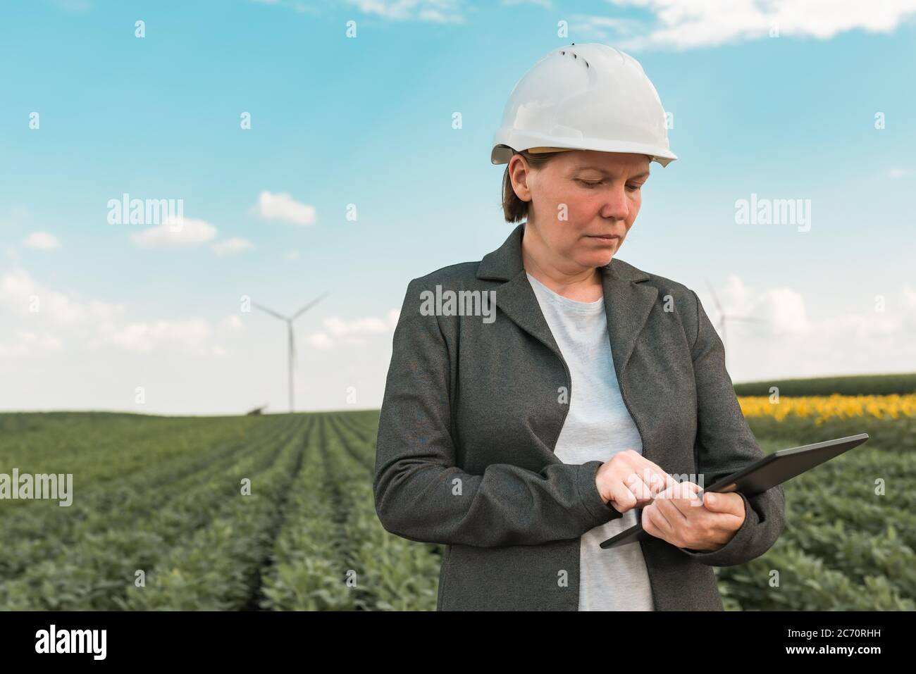 Female engineer with tablet computer on modern wind turbine farm during ...