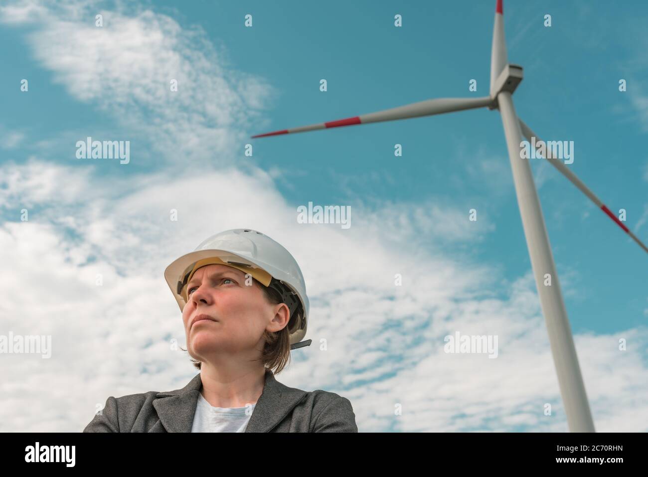 Portrait of female engineer on modern wind turbine farm during ...