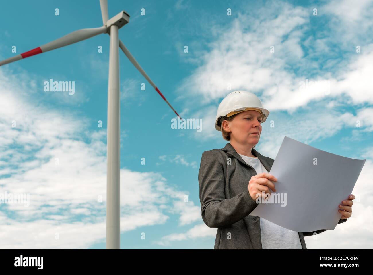 Portrait of female engineer on modern wind turbine farm during ...