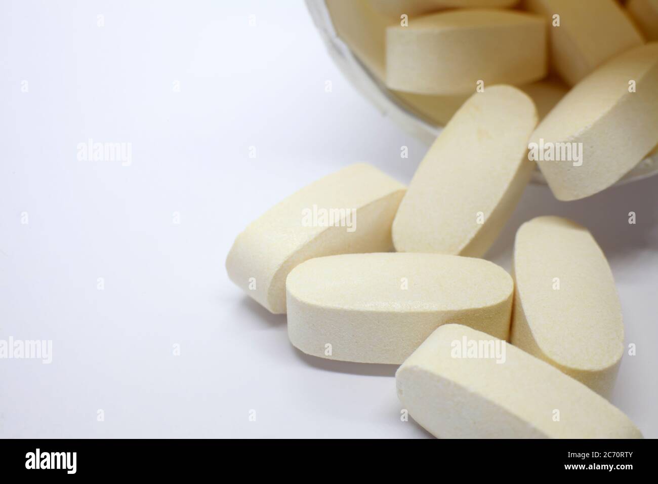 Tablets spilling from container Stock Photo - Alamy
