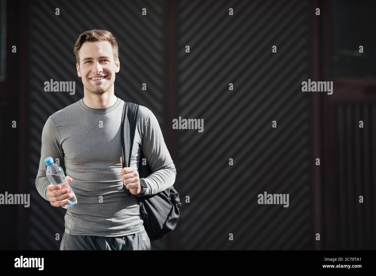 Guy with bottle of water ready for training. Smiling athlete in ...