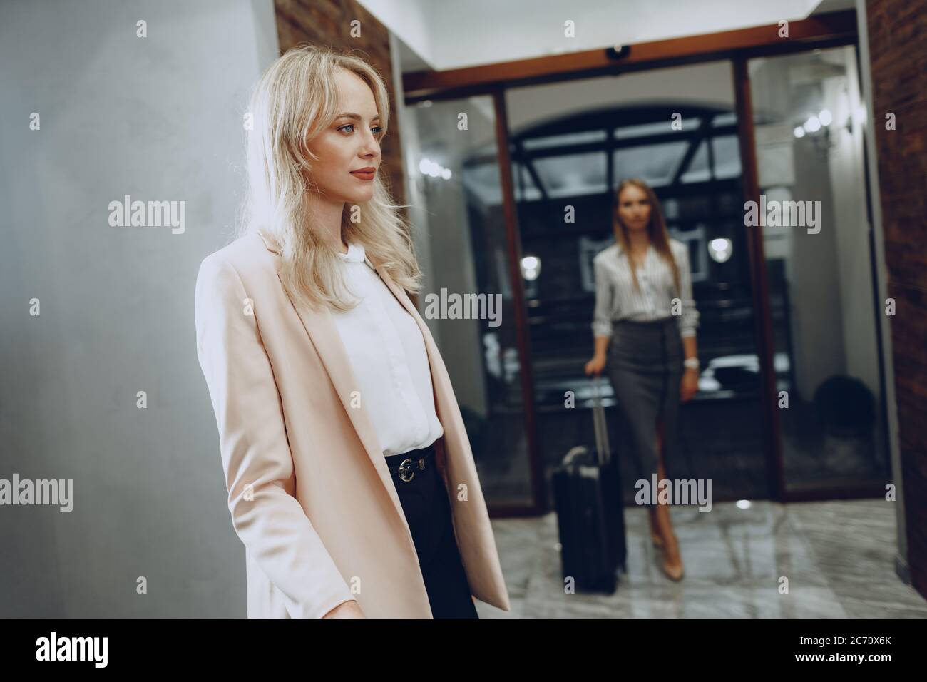 Two young women in formal clothes entering hotel lobby Stock Photo - Alamy