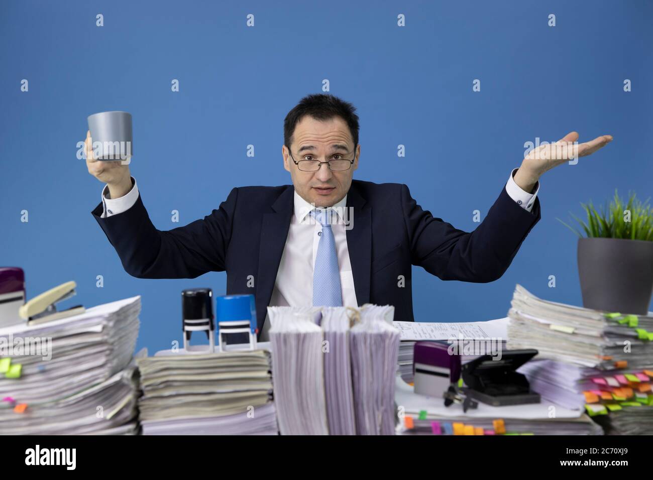 The office manager in a suit and glasses spreads his arms wide and ...