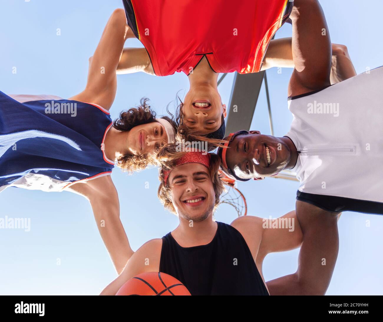 Smiling basketballers putting their heads together in unity outside ...