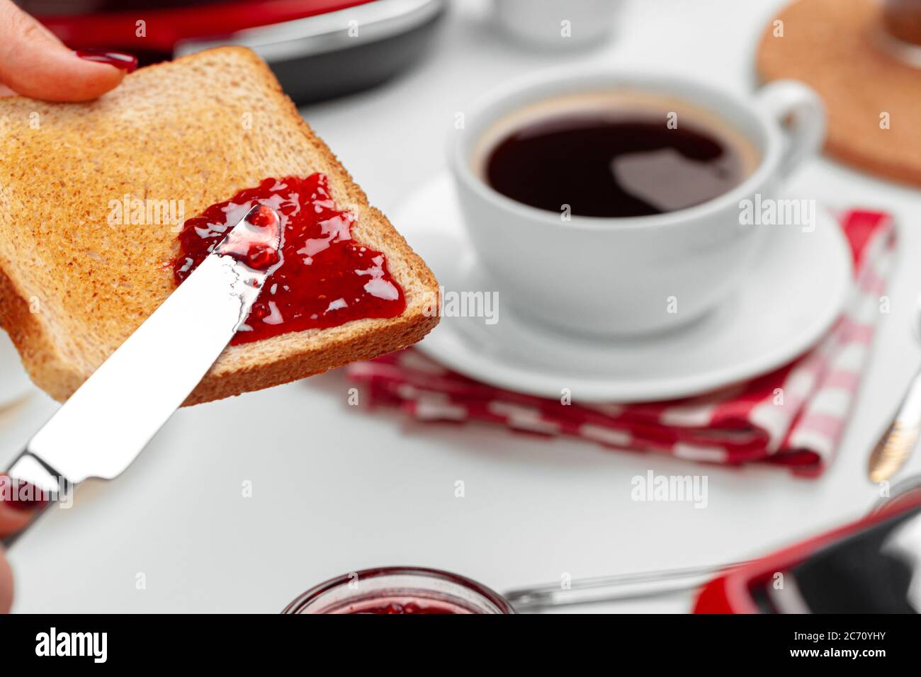 Female hand spresding strawberry jam on baked toast Stock Photo - Alamy