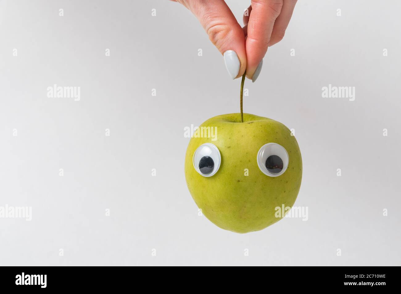 Fingers holding Apple with funny face. Apple on white background Stock ...