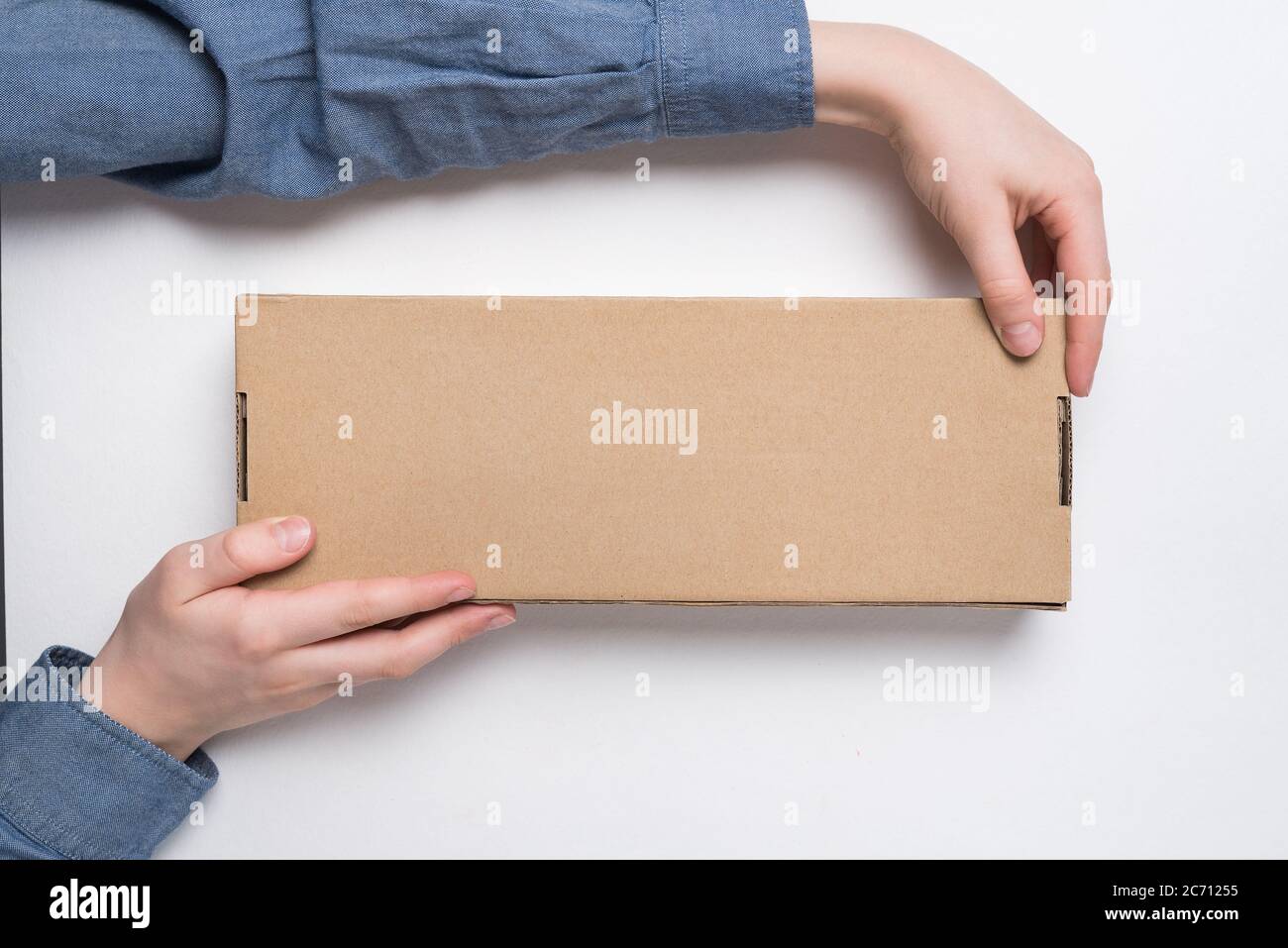 Child holds rectangular craft paper box on white background. Parcel ...