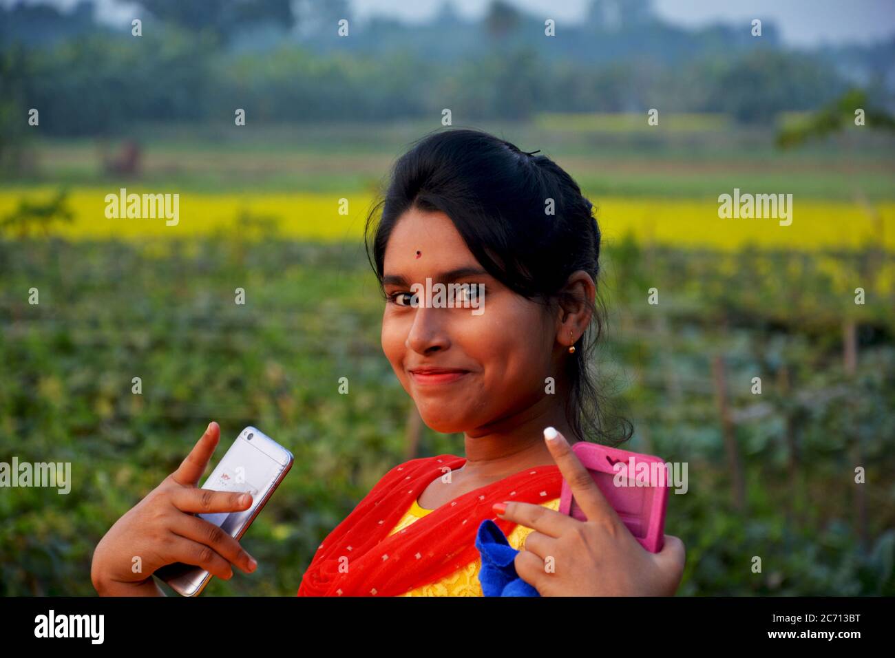 An Indian teenager girl smiling in a rural village field, selective ...