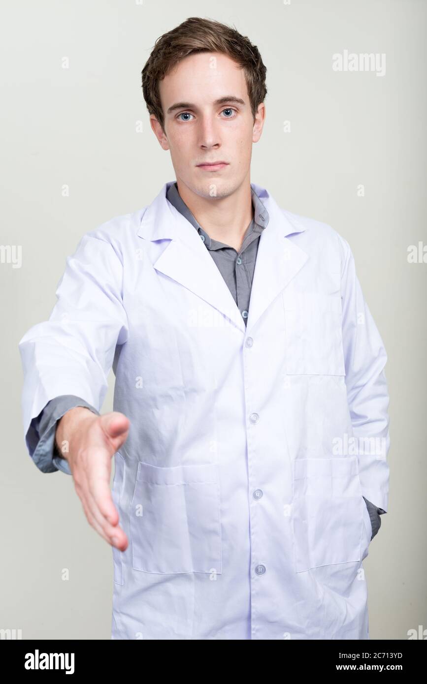 Portrait of young handsome man doctor giving handshake Stock Photo - Alamy