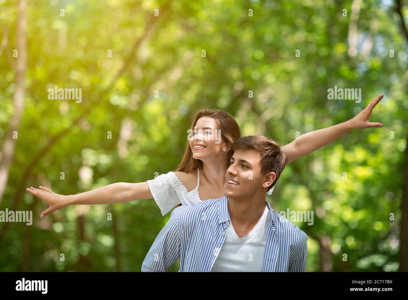 Caring boyfriend carrying girlfriend on his back in nature, copy space ...