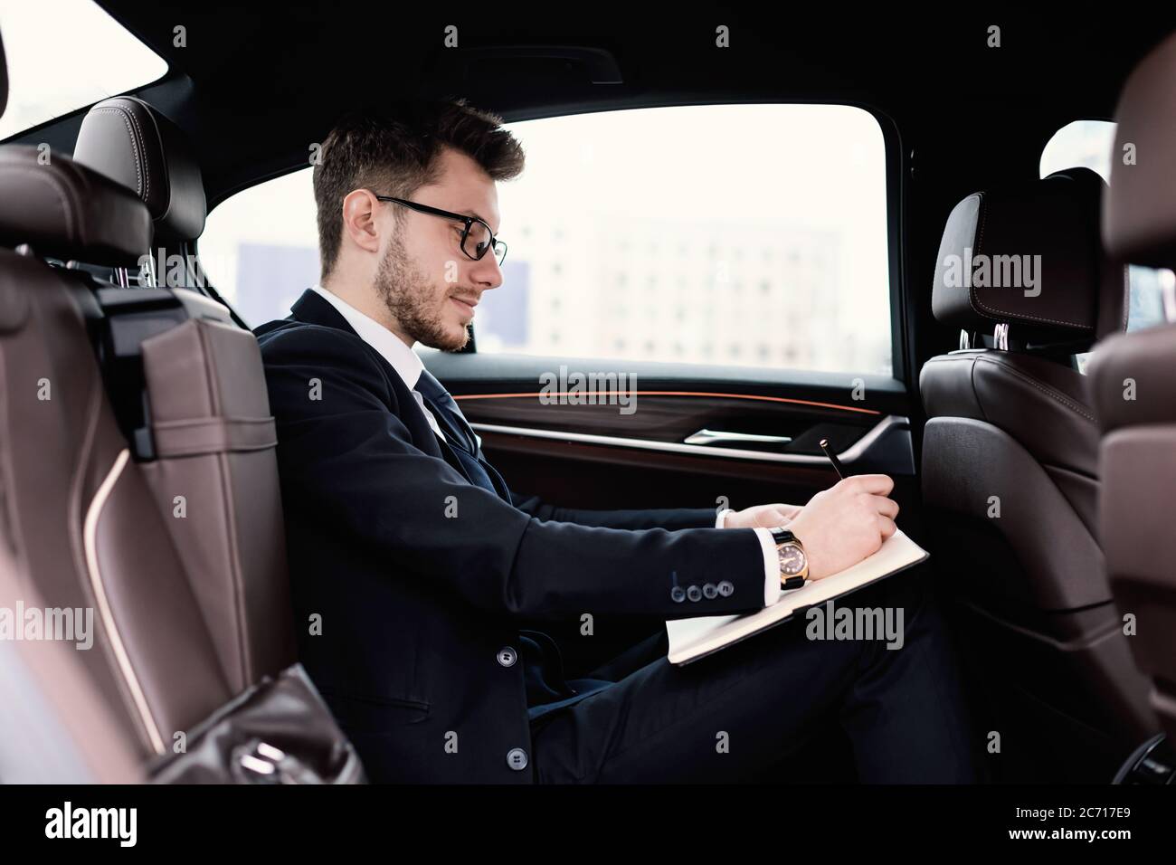 Business man writing in notebook in luxury car Stock Photo - Alamy