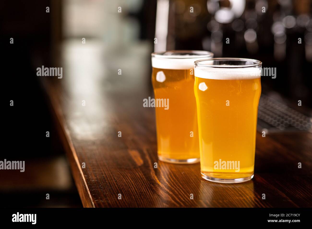 Cold delicious drinks. Two glasses of light beer on wooden bar counter ...