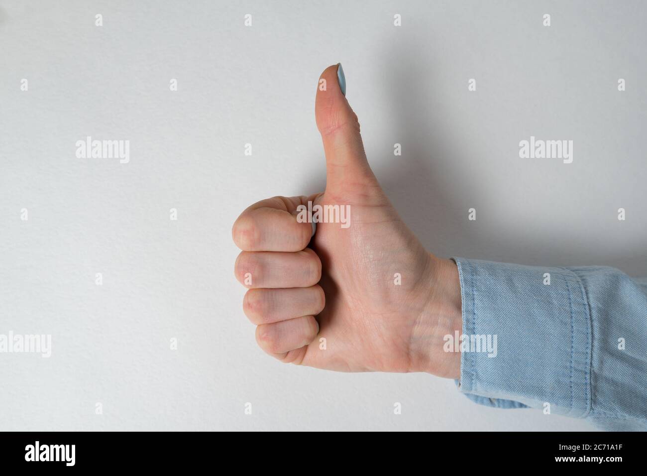 Closeup of female hand showing thumb up on white background. Well done ...