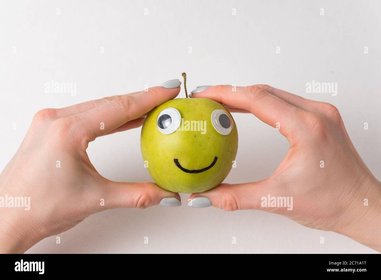 Hands holding cute little Apple with Googly eyes and drawn smile. Apple ...