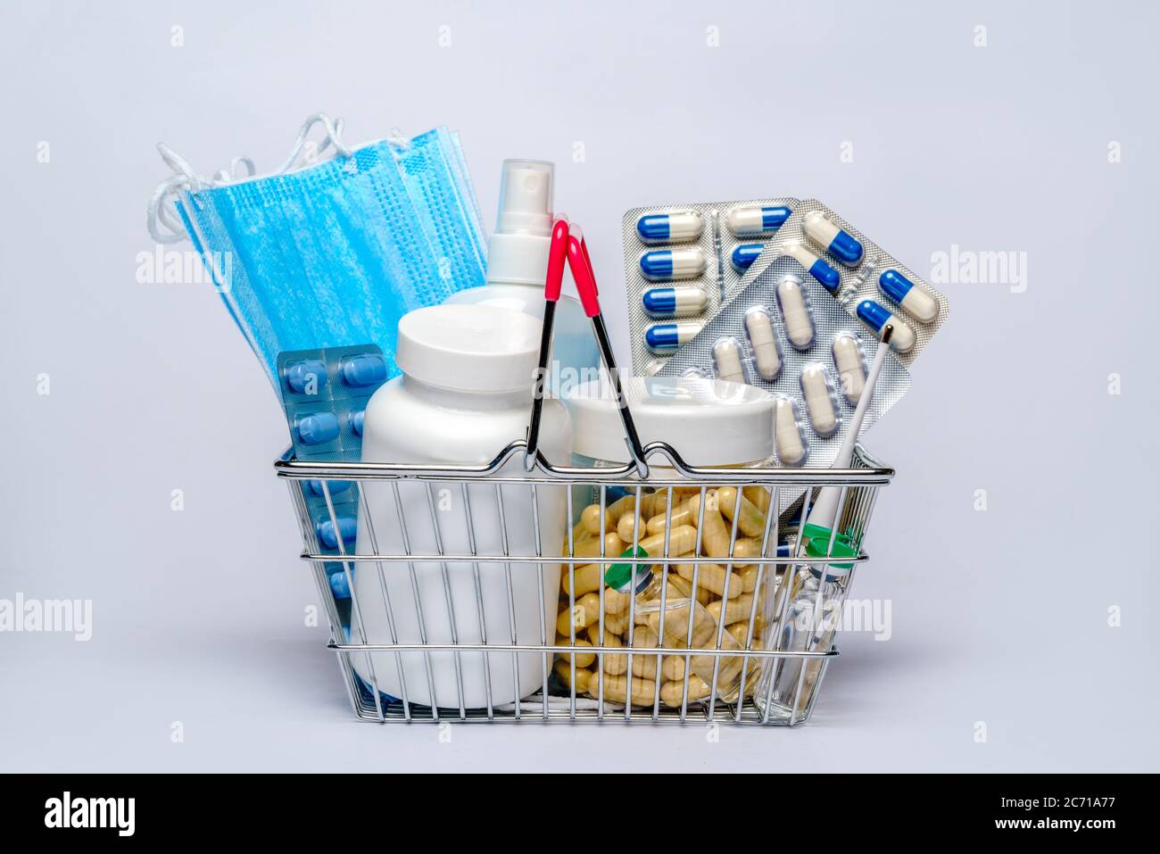 Shopping basket cart full of pills and medical supplies over light grey ...