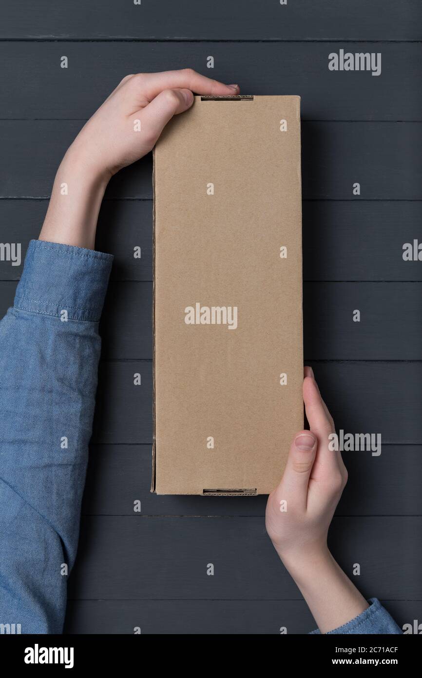 Craft rectangular box in children's hands on black background. Top view ...