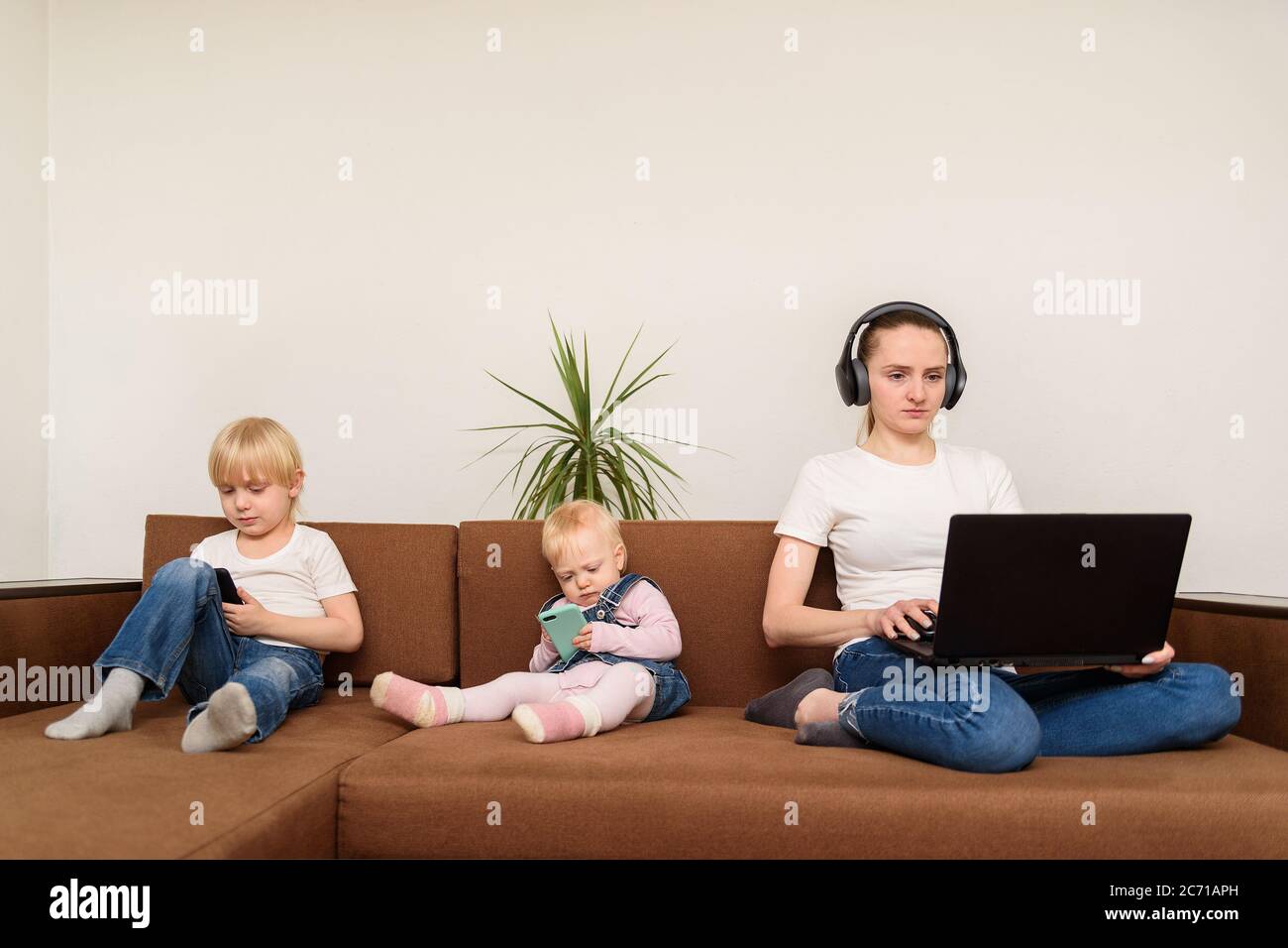 Mother sitting with laptop and working while children are playing ...