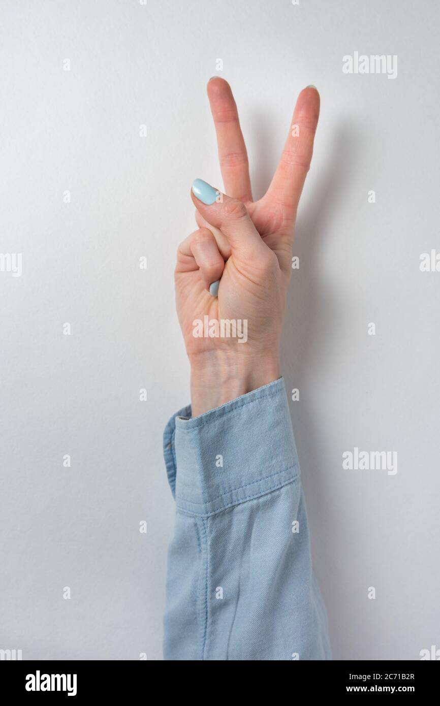 Female hand showing gesture of victoria. Two fingers raised up on white ...