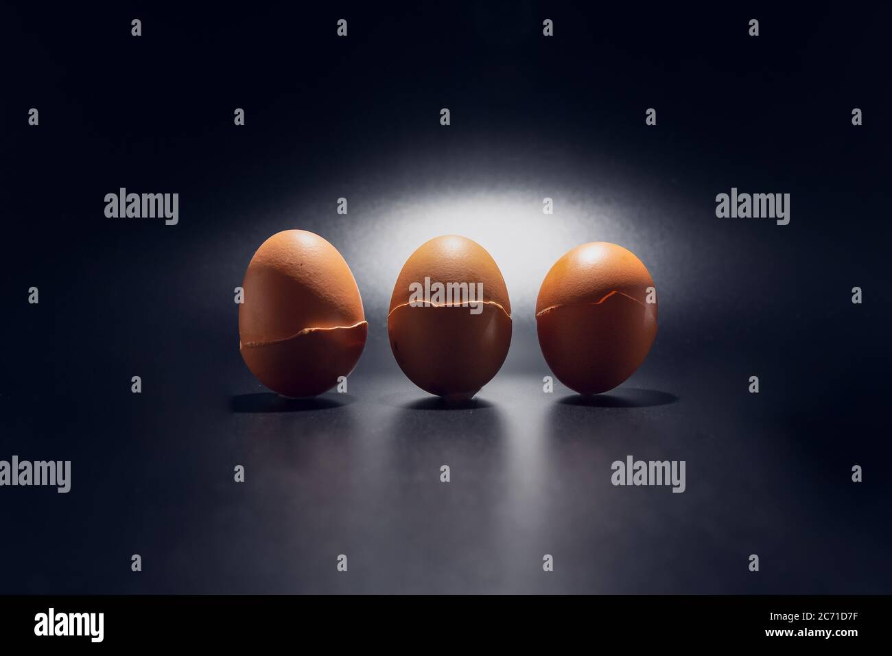 Three broken chicken eggshells in line isolated on black background ...