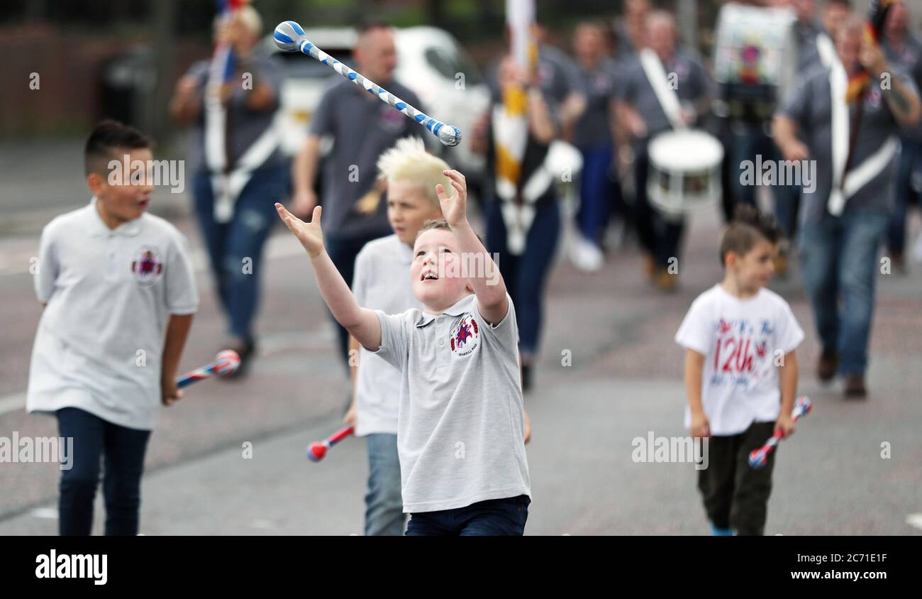 Children twirl batons in front of a marching band on Shankill Road ...