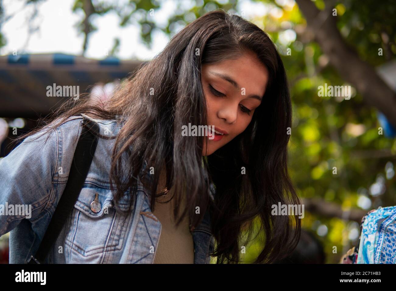 Outdoor low angle image of happy girl looking down in outdoor at day ...