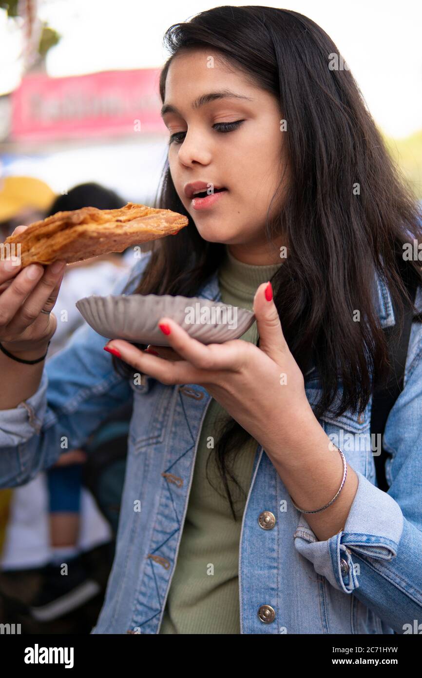 Girl eating street food potato puff pastry (Aloo patties) at outdoor ...