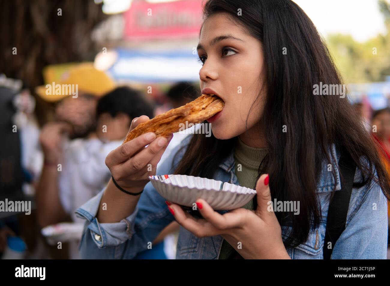 Girl eating street food potato puff pastry (Aloo patties) at outdoor ...