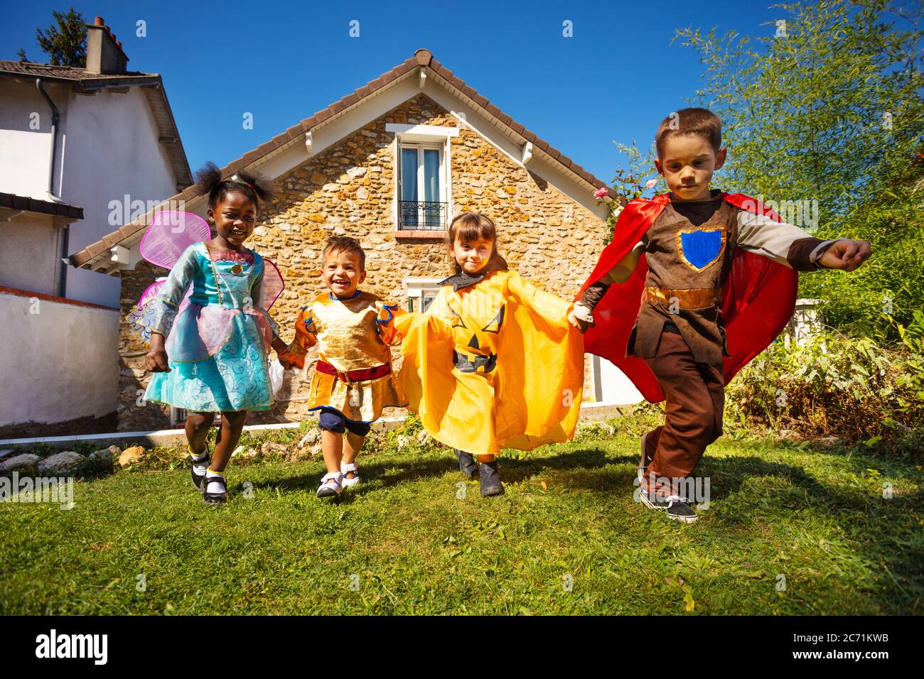 Group of little kids run in Halloween costumes on the lawn before the ...
