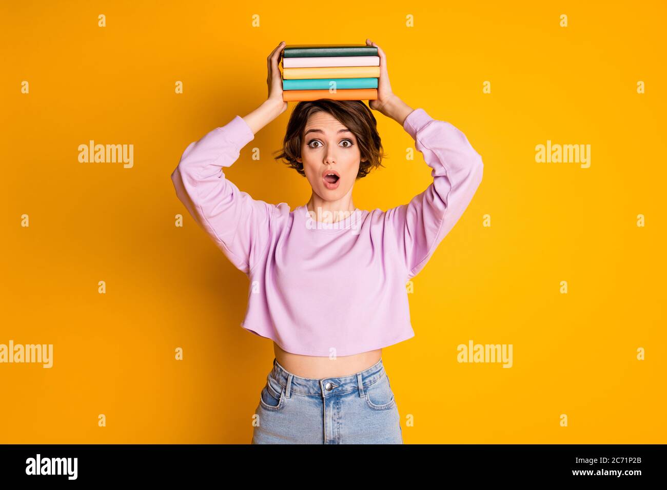 Portrait of astonished high school student girl put pile copybooks ...