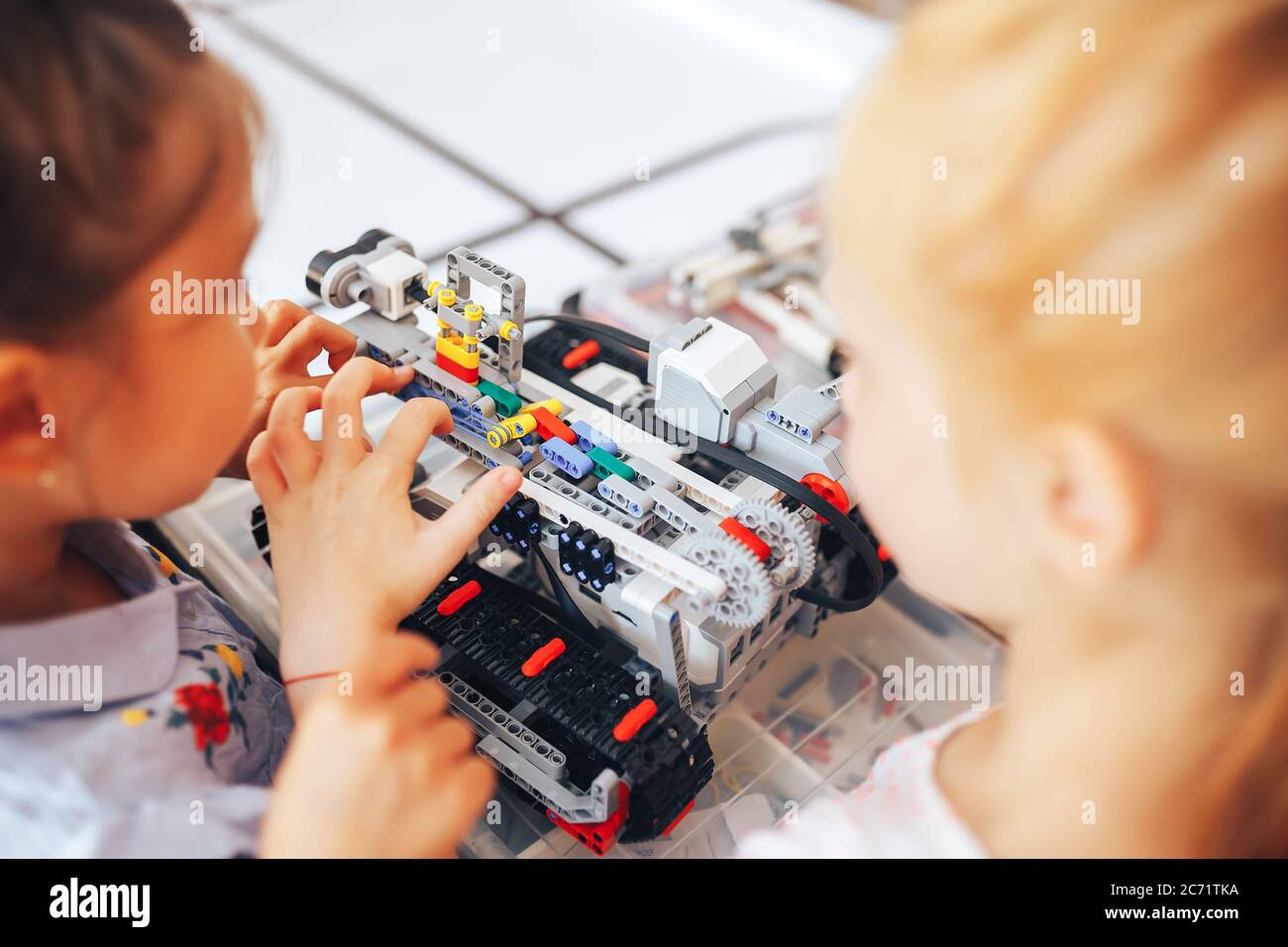 Two schoolgirls study in a robotics class, assemble a robot constructor ...
