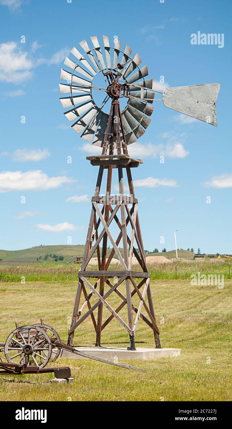 Vintage windmill against a blue sky on rural farmland in this vertical ...