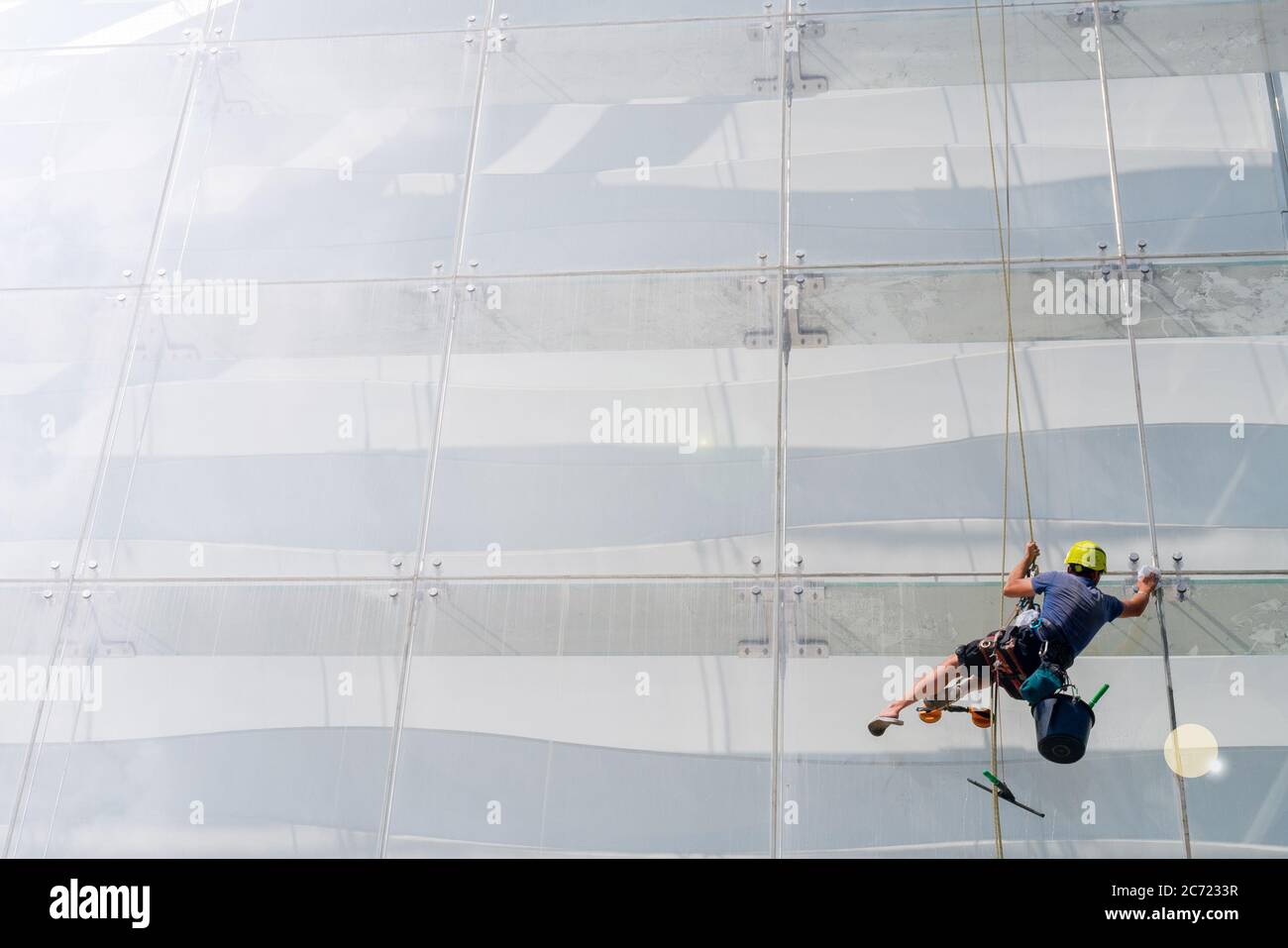 Window washer works on the wall of a glass building Stock Photo - Alamy