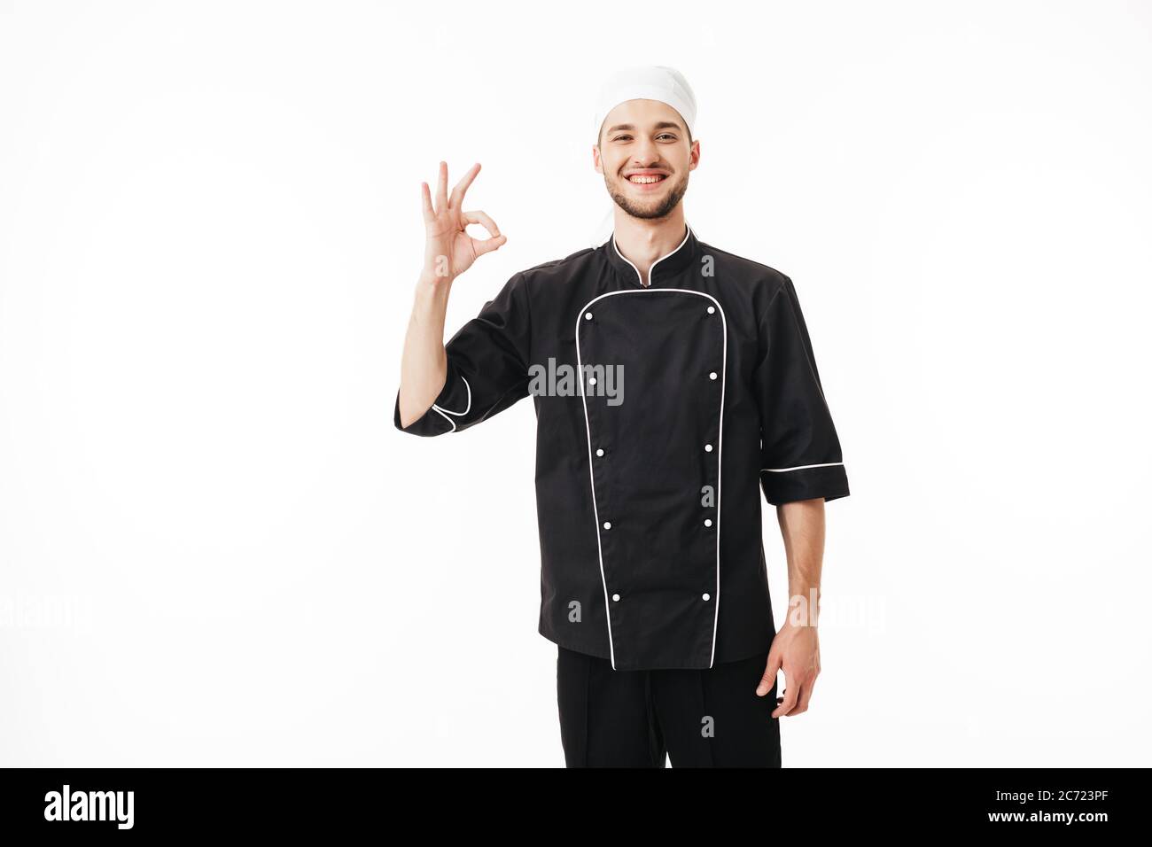 Young smiling man chef in black uniform happily looking in camera ...